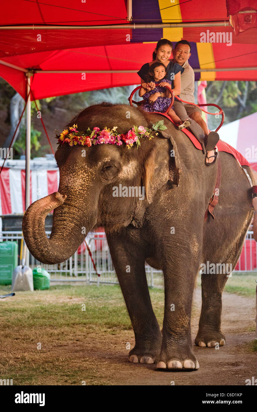 An Asian family rides on a costumed elephant at the amusement park of ...
