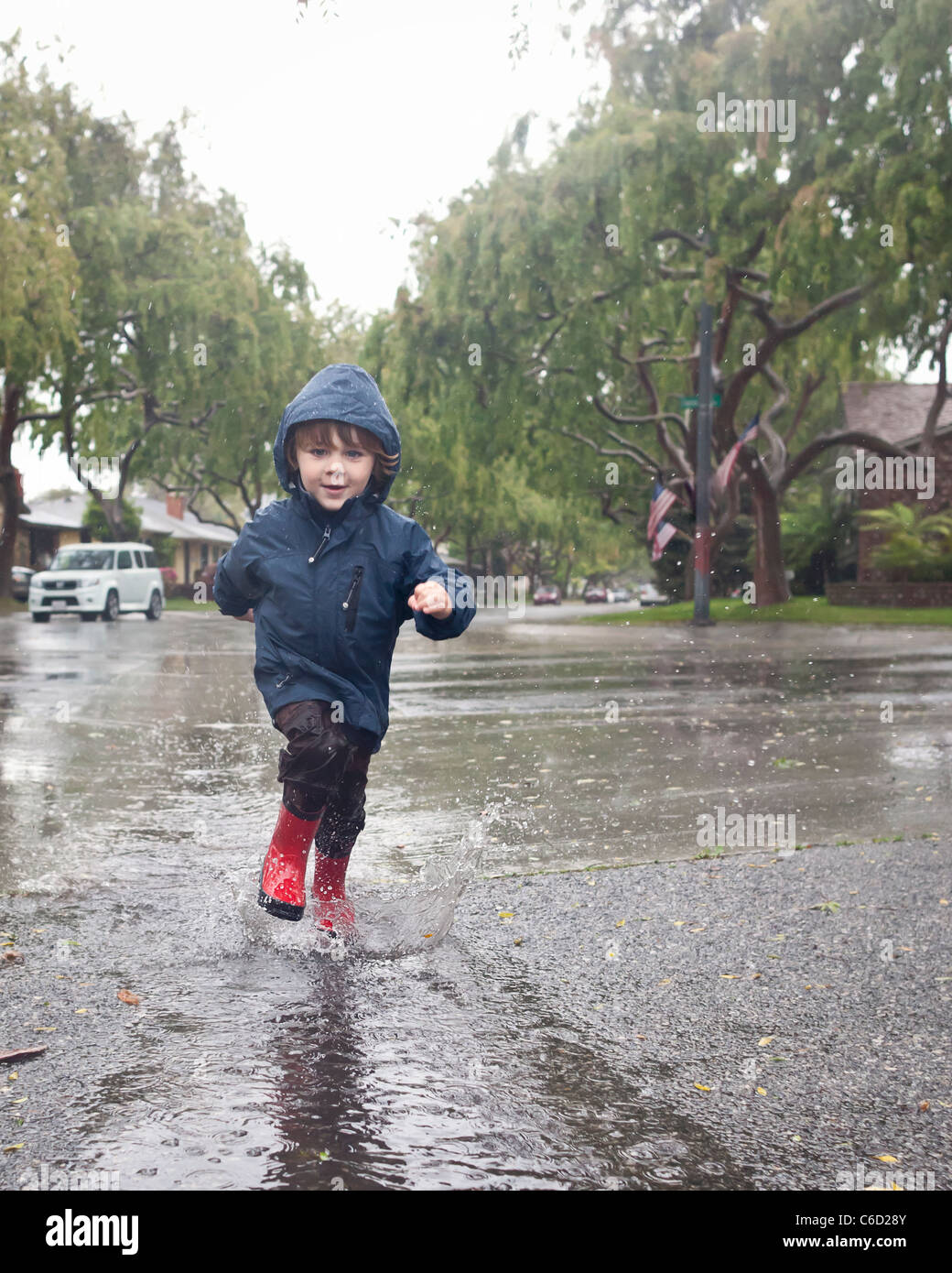 Caucasian boy splashing in rain puddle Stock Photo - Alamy