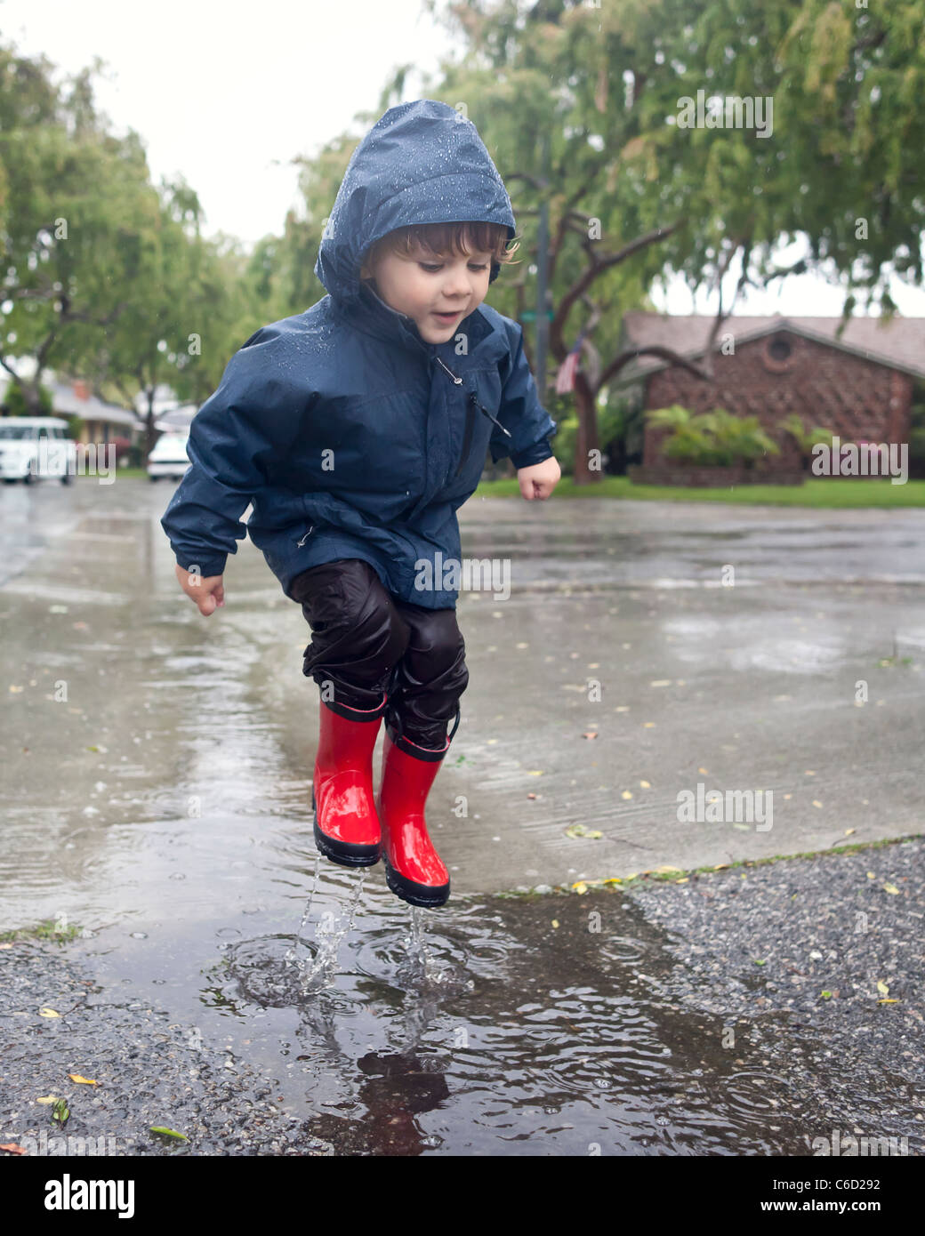 Caucasian boy jumping in rain puddle Stock Photo - Alamy
