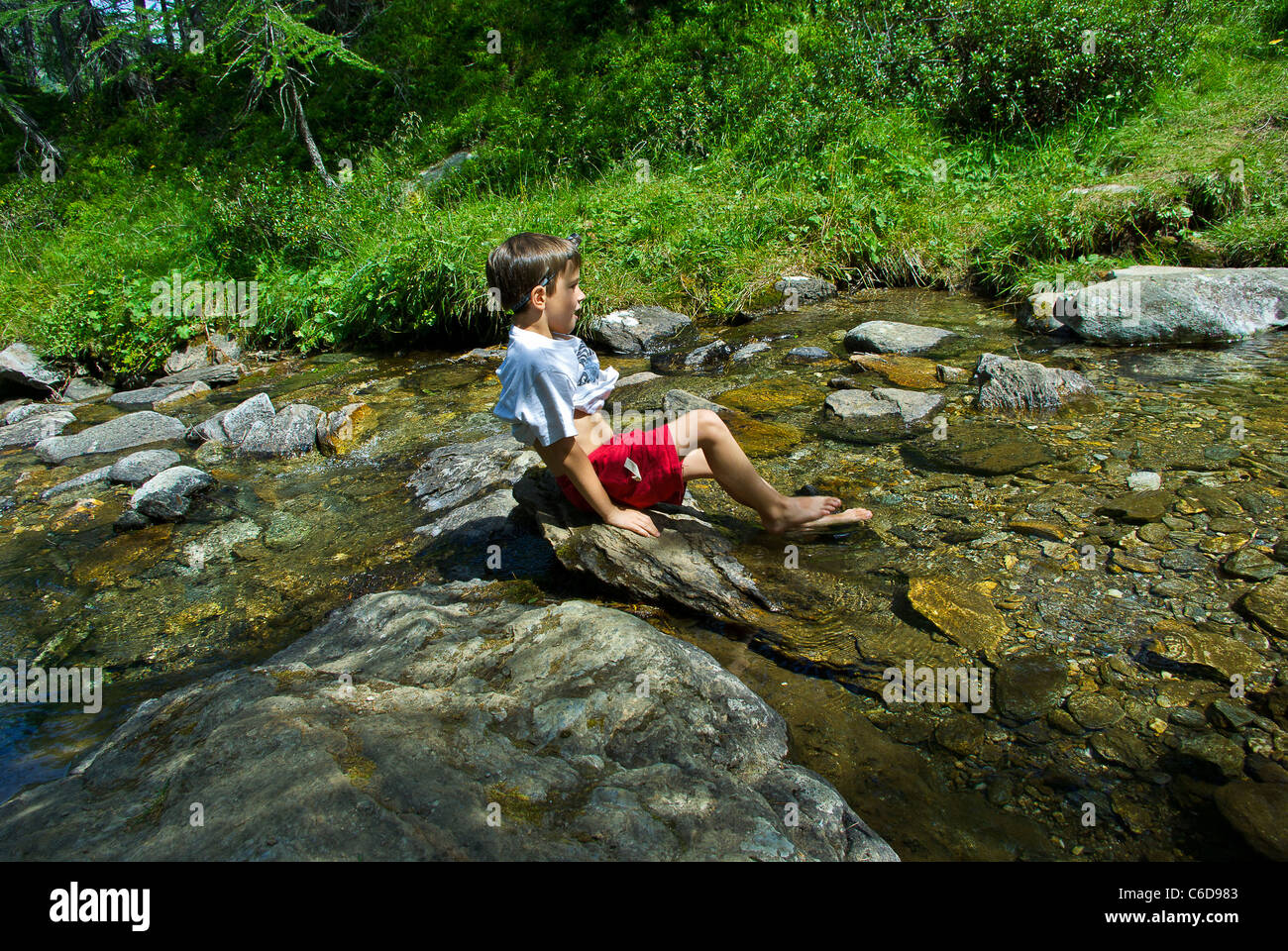 child sitting on the riverbank Stock Photo - Alamy