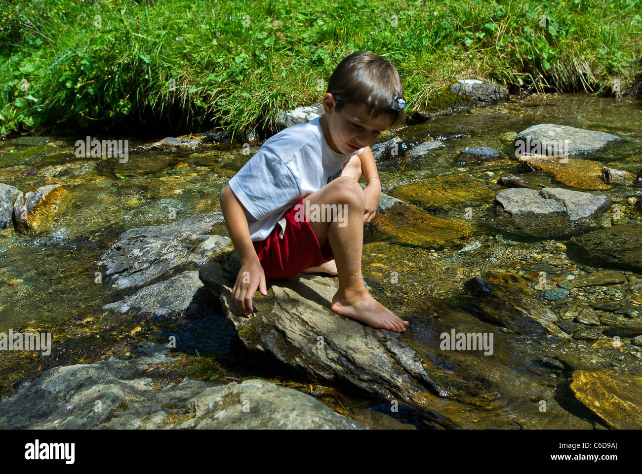 child sitting on the riverbank Stock Photo - Alamy