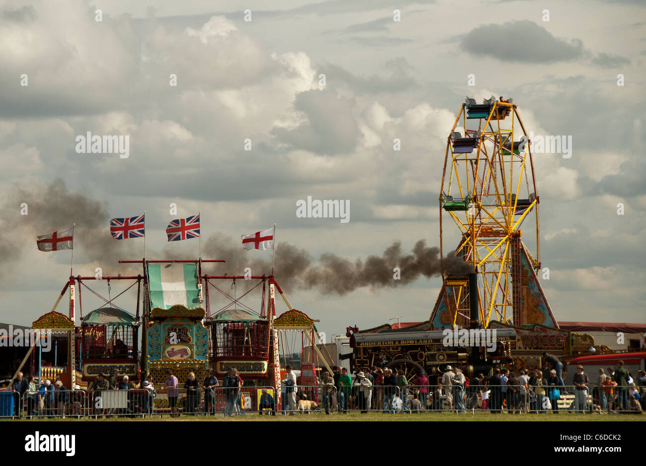 Fairground big wheel pictured against a cloudy sky, with flags flying ...
