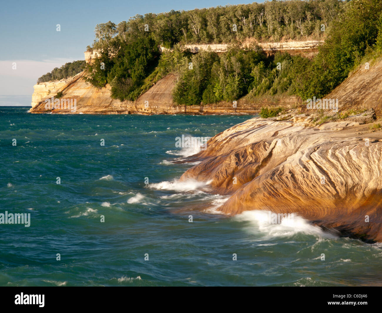 Waves sweep over the sandstone coastline of Pictured Rocks National ...