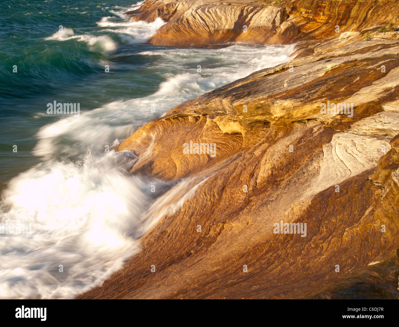 Waves sweep over the sandstone coastline of Pictured Rocks National ...