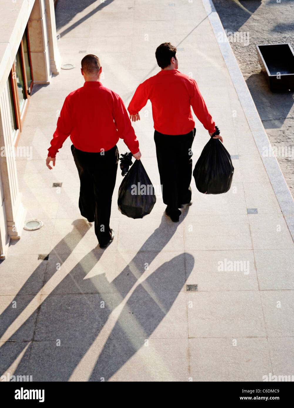 Two men taking out the garbage Stock Photo - Alamy