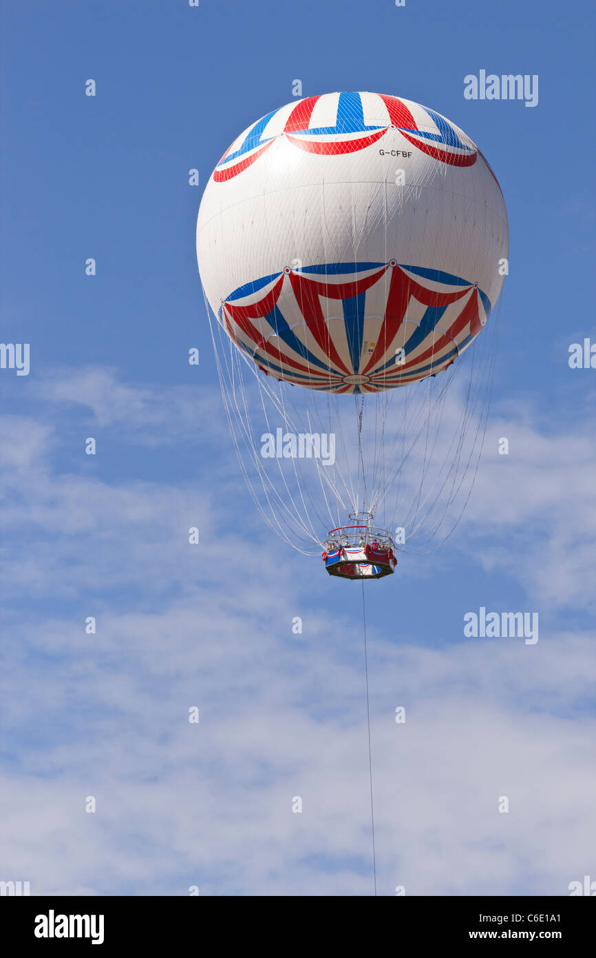 Floating helium observation balloon with blue sky and wispy clouds ...