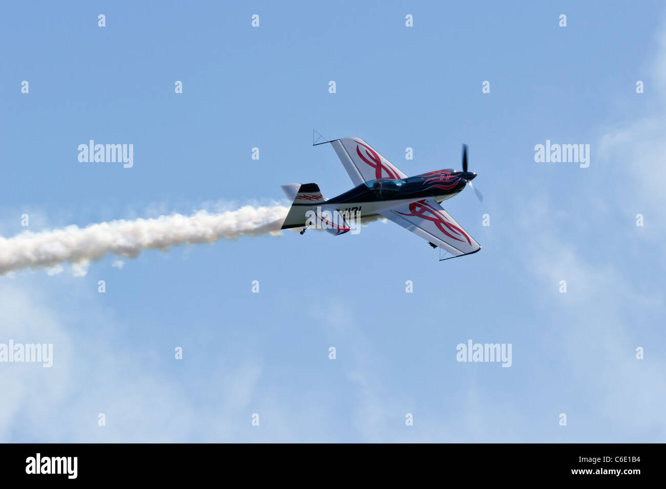 Single Stunt Plane aircraft with smoke trail performing aerobatics ...