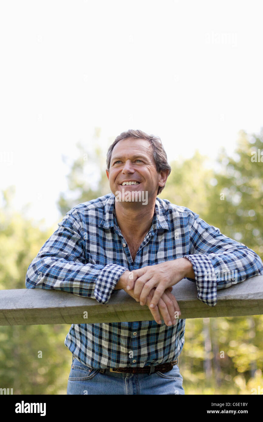Caucasian man leaning on wooden fence Stock Photo - Alamy