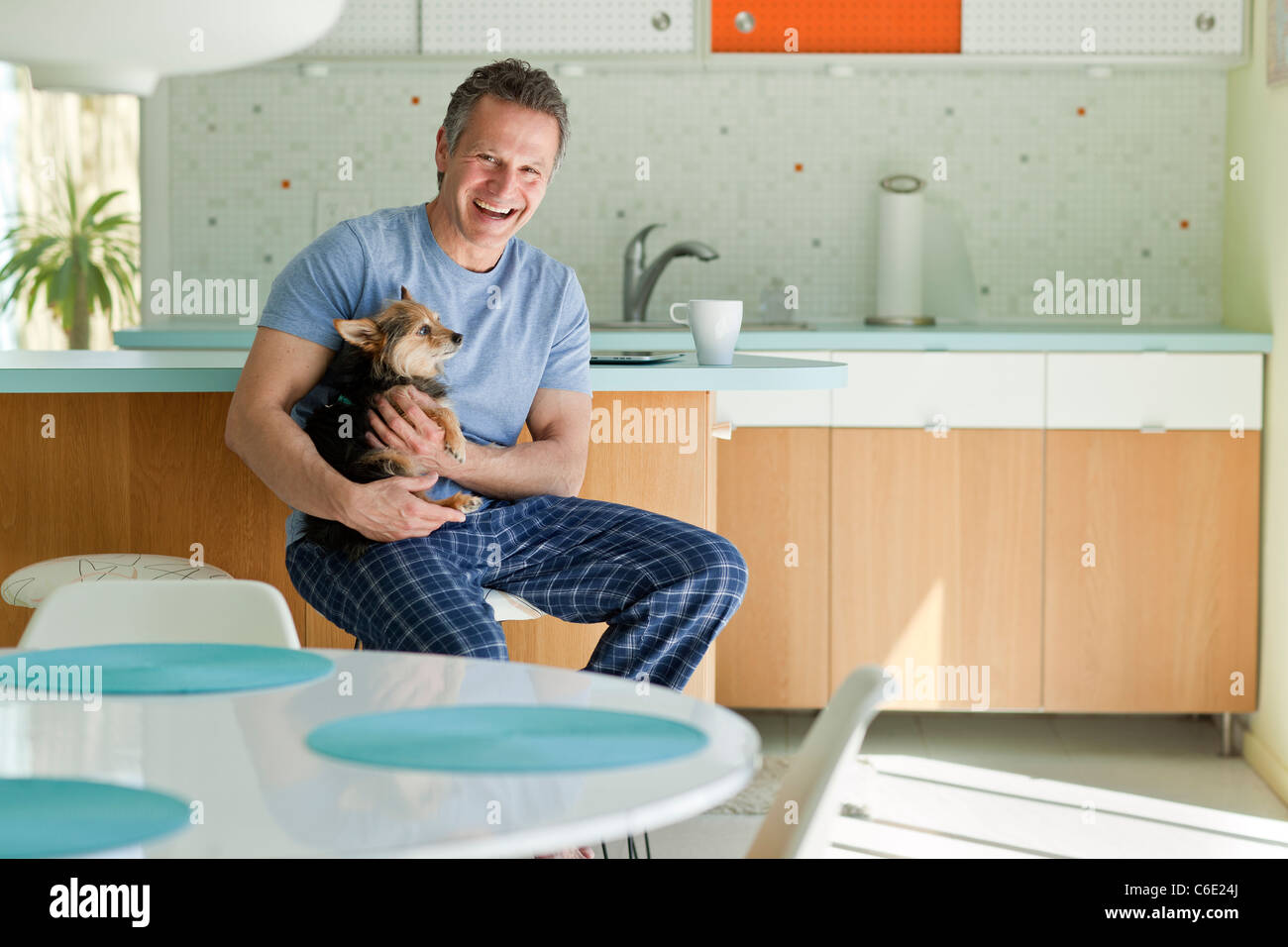 Man sitting in kitchen with dog Stock Photo - Alamy