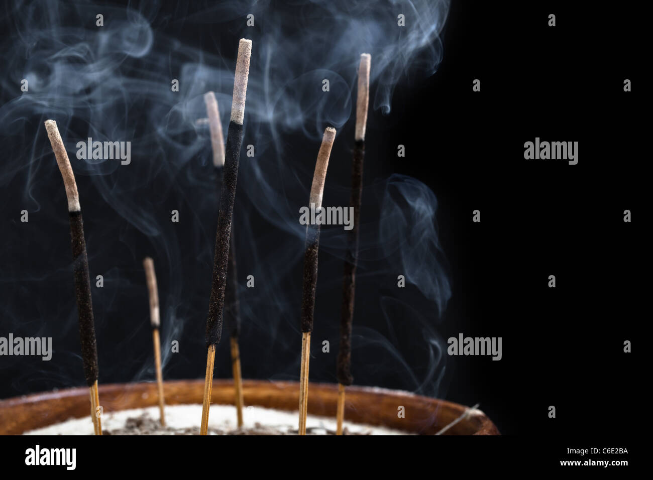 Burning incense sticks with smoke in bowl over black background Stock ...