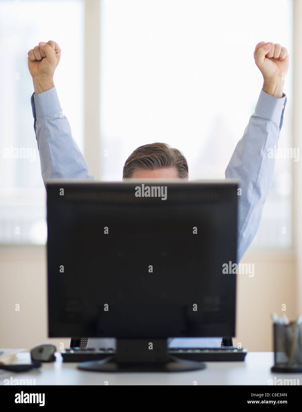 USA, New Jersey, Jersey City, Businessman raising hands from behind ...