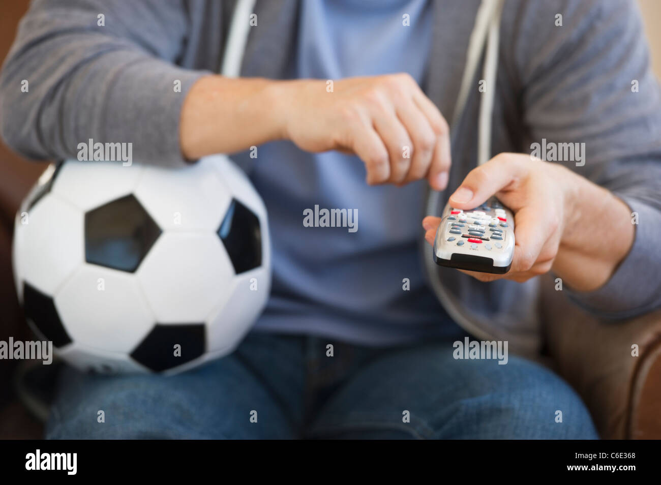 Man holding soccer ball and remote control Stock Photo - Alamy