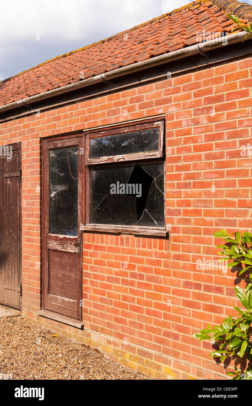 A smashed window in a Uk garden shed Stock Photo - Alamy