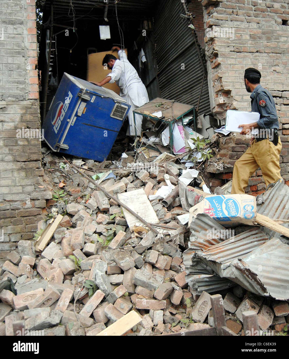 A plain-clothes policeman inspects a damaged portion of canteen which ...