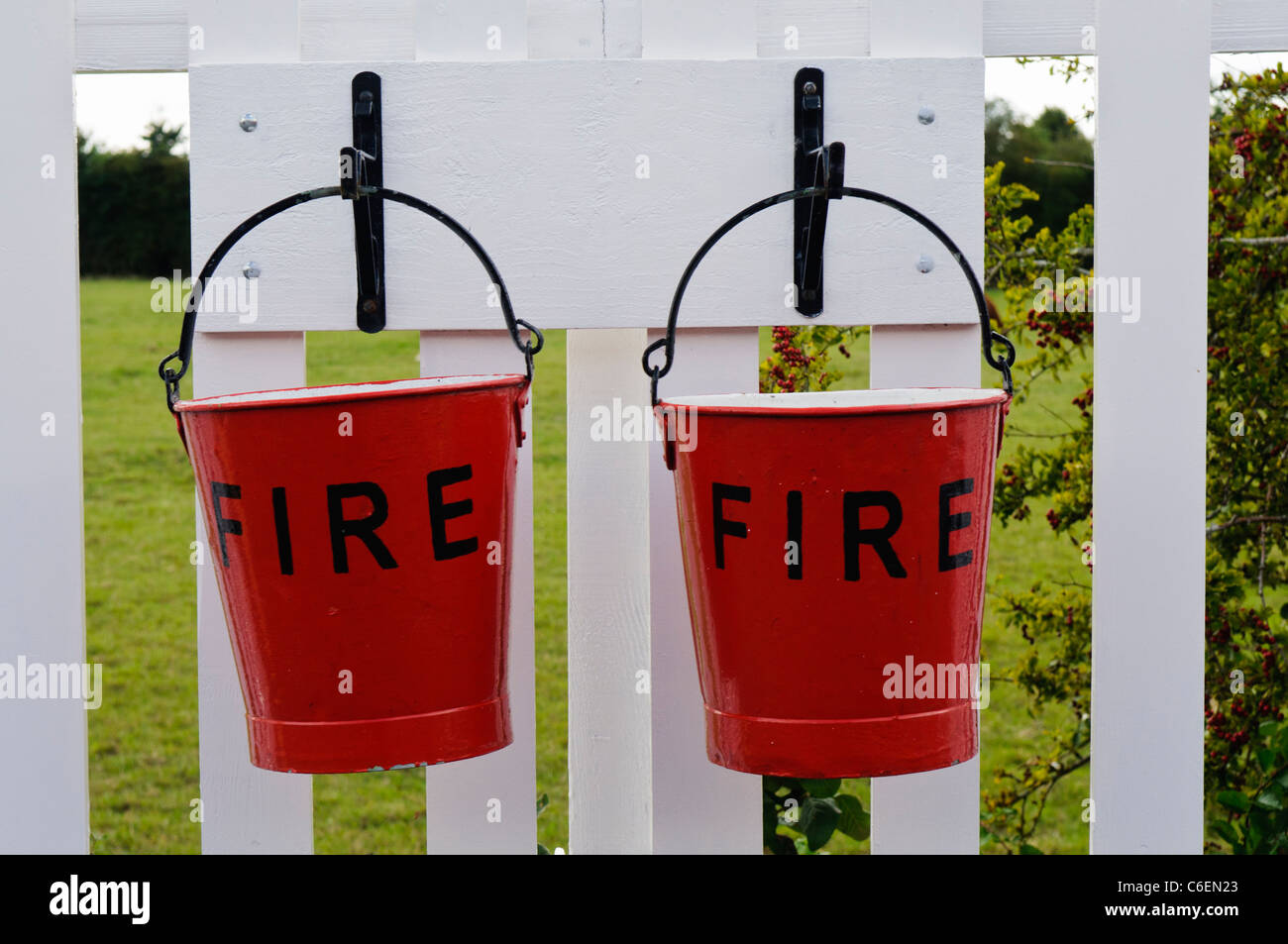 Two fire buckets hanging by hooks from a fence Stock Photo - Alamy