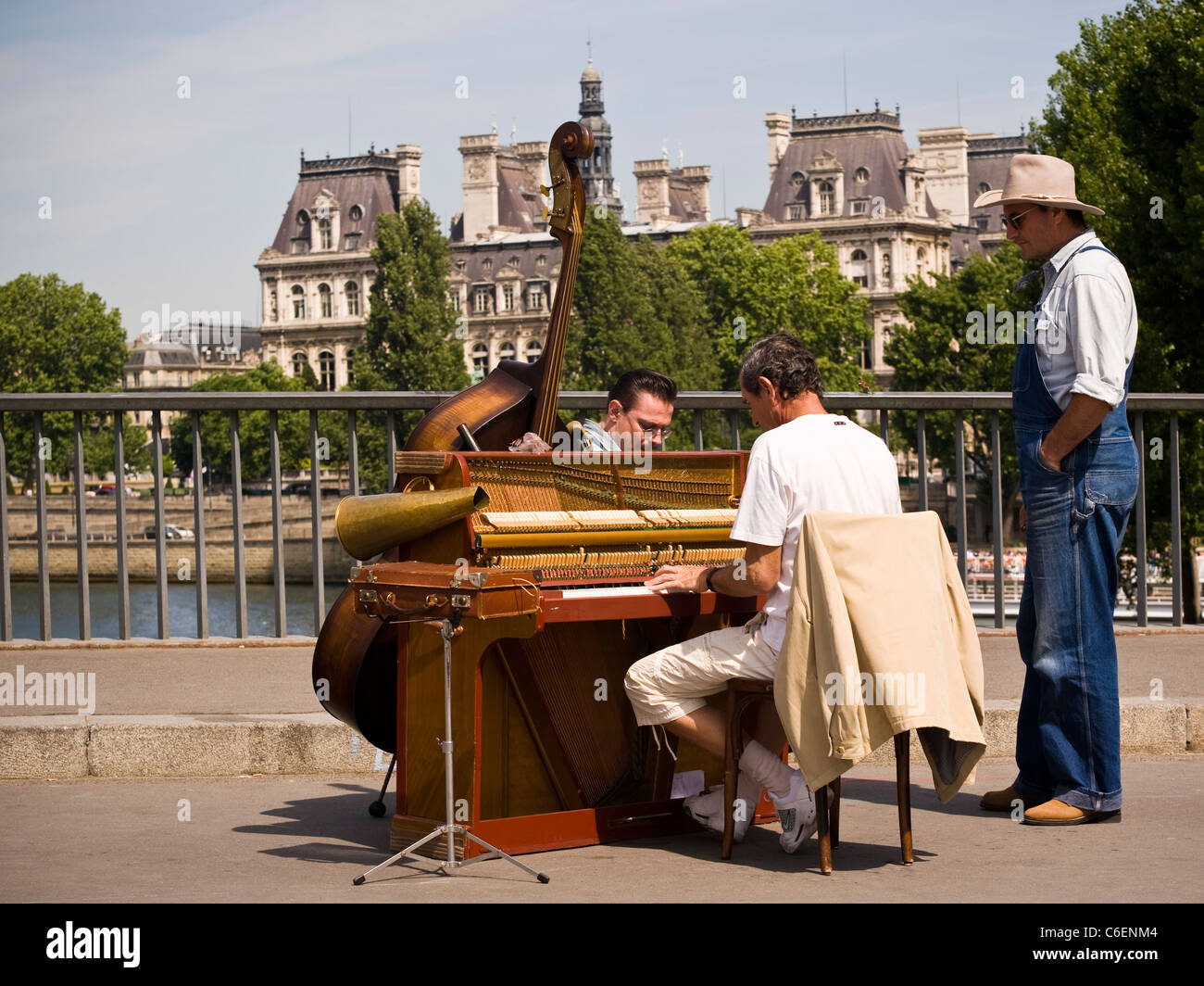 Two musicians play different instruments on a bridge in the center of ...