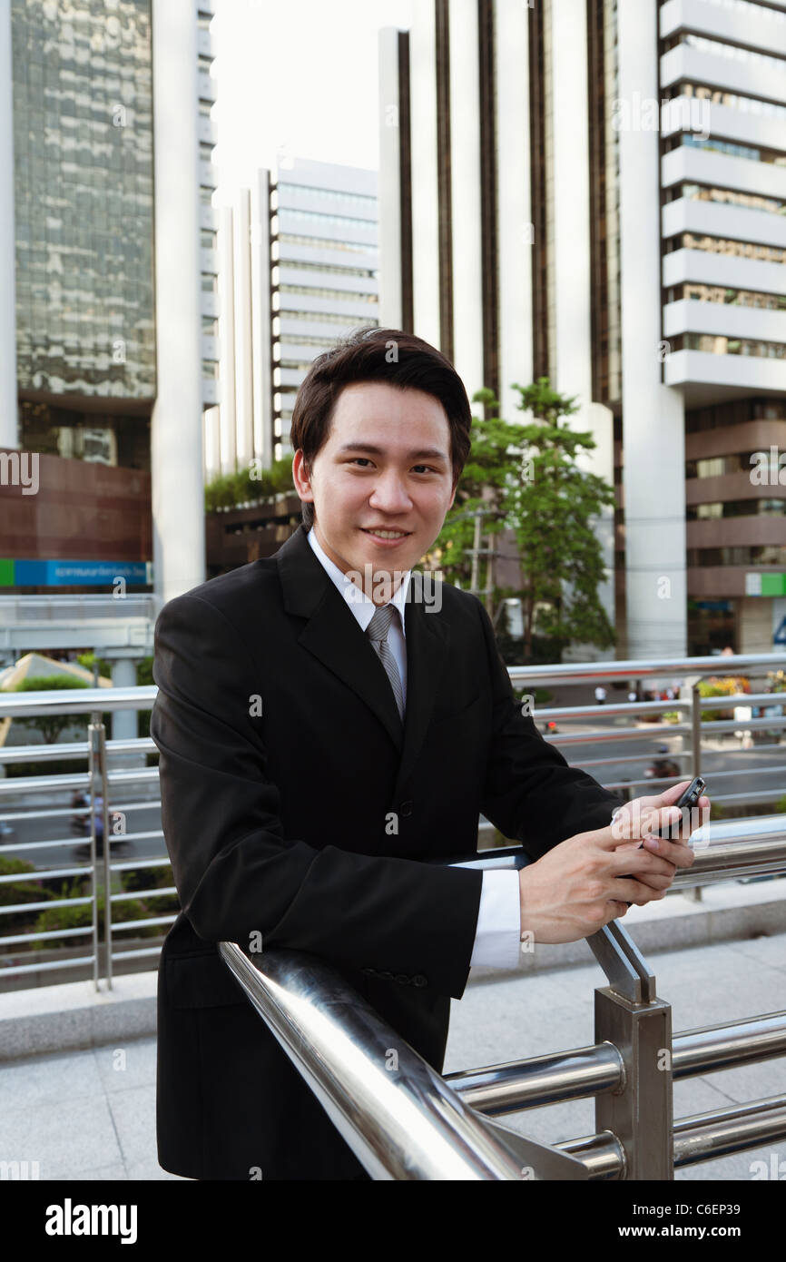 Asian businessman text messaging on cell phone outdoors Stock Photo - Alamy