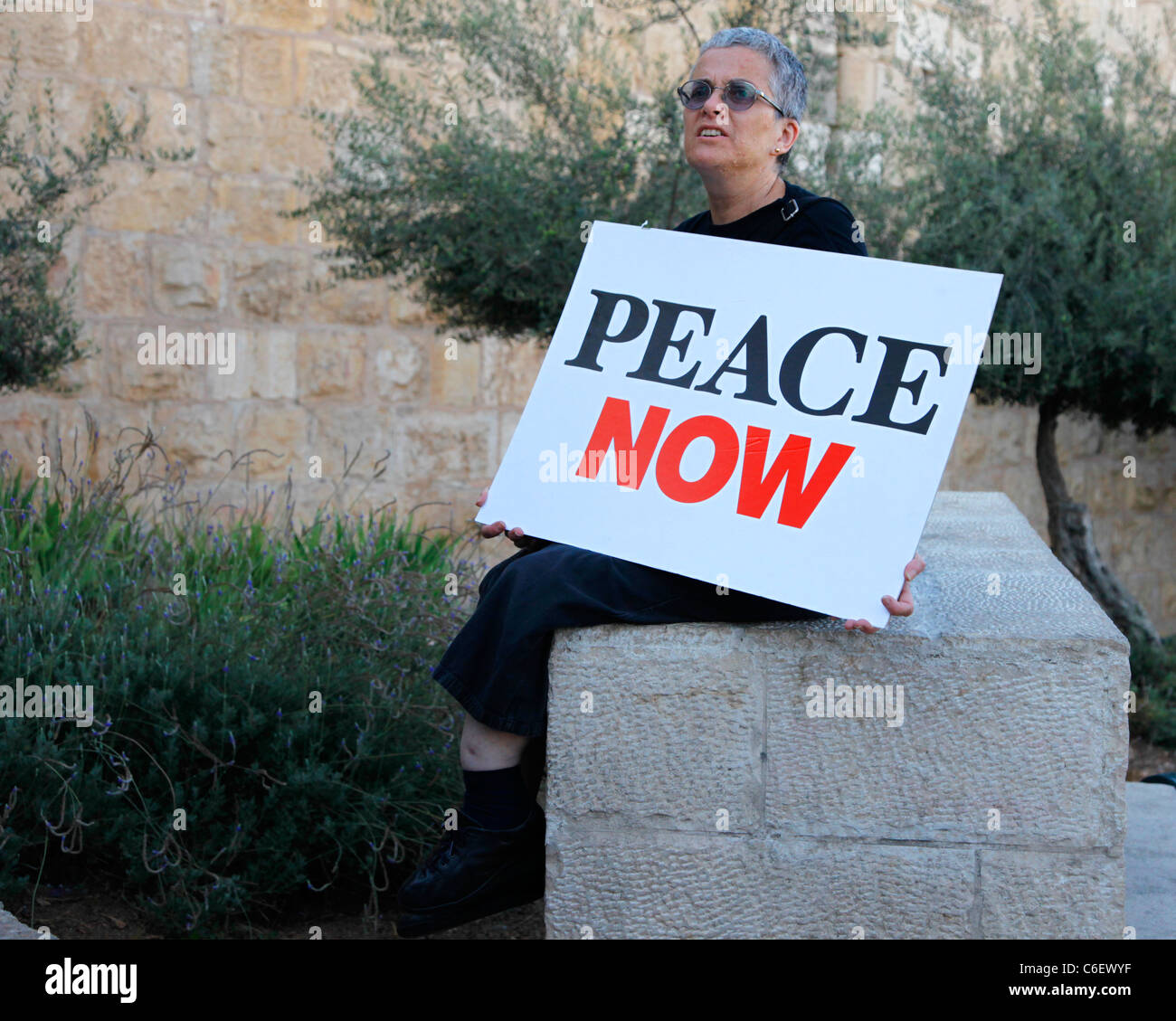 An Israeli left-wing activist holds a sign which reads Peace Now as she ...