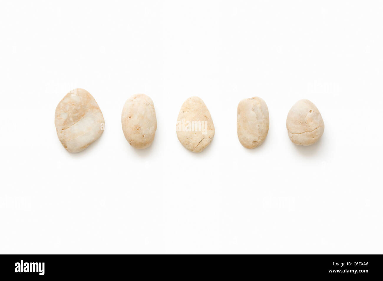 Simple arrangement of five pebbles lined up in a row on a white ...