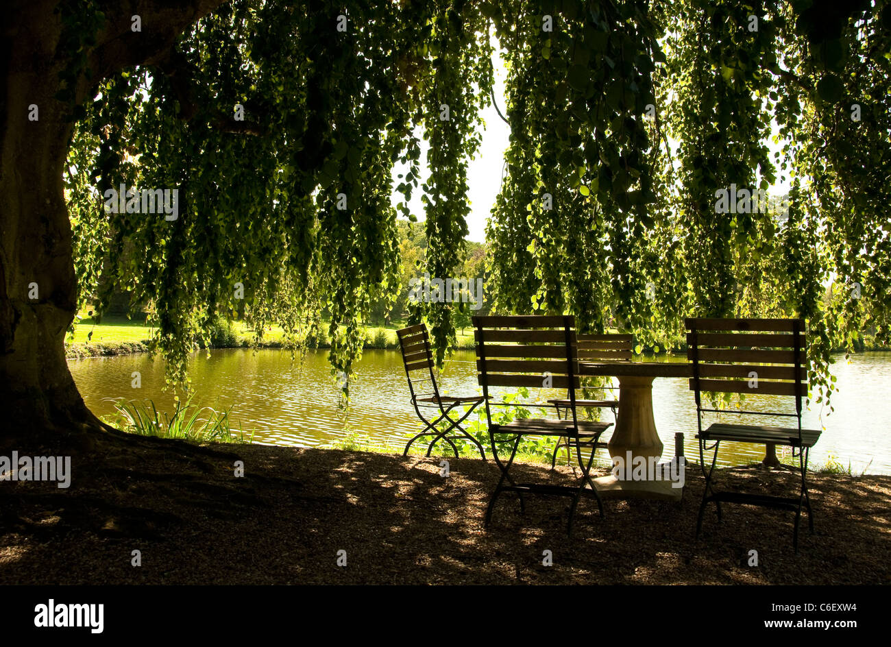 Stone table and wood chairs next to a pond Stock Photo - Alamy