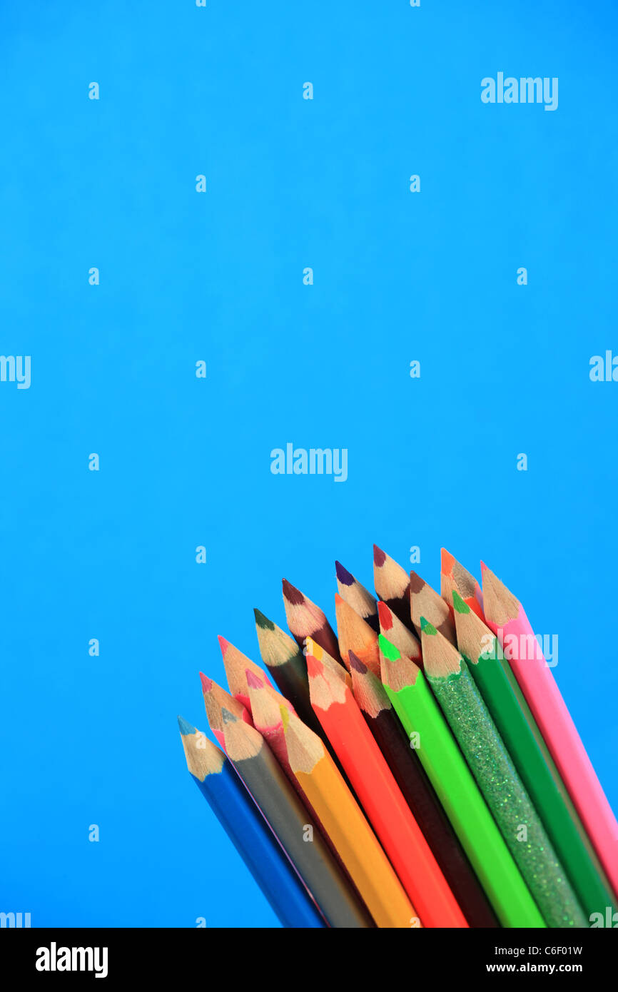 Multi coloured pencils in a pot, blue background Stock Photo - Alamy