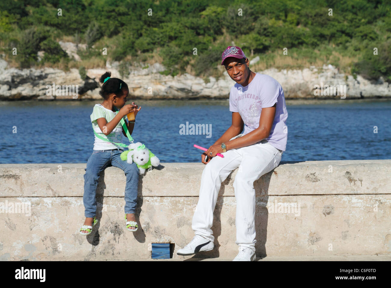 African Cuban father and little daughter sitting on the wall & spending ...