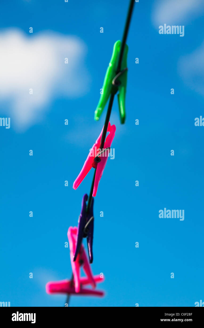 A row of colourful clothes pegs hanging on a washing line against a ...