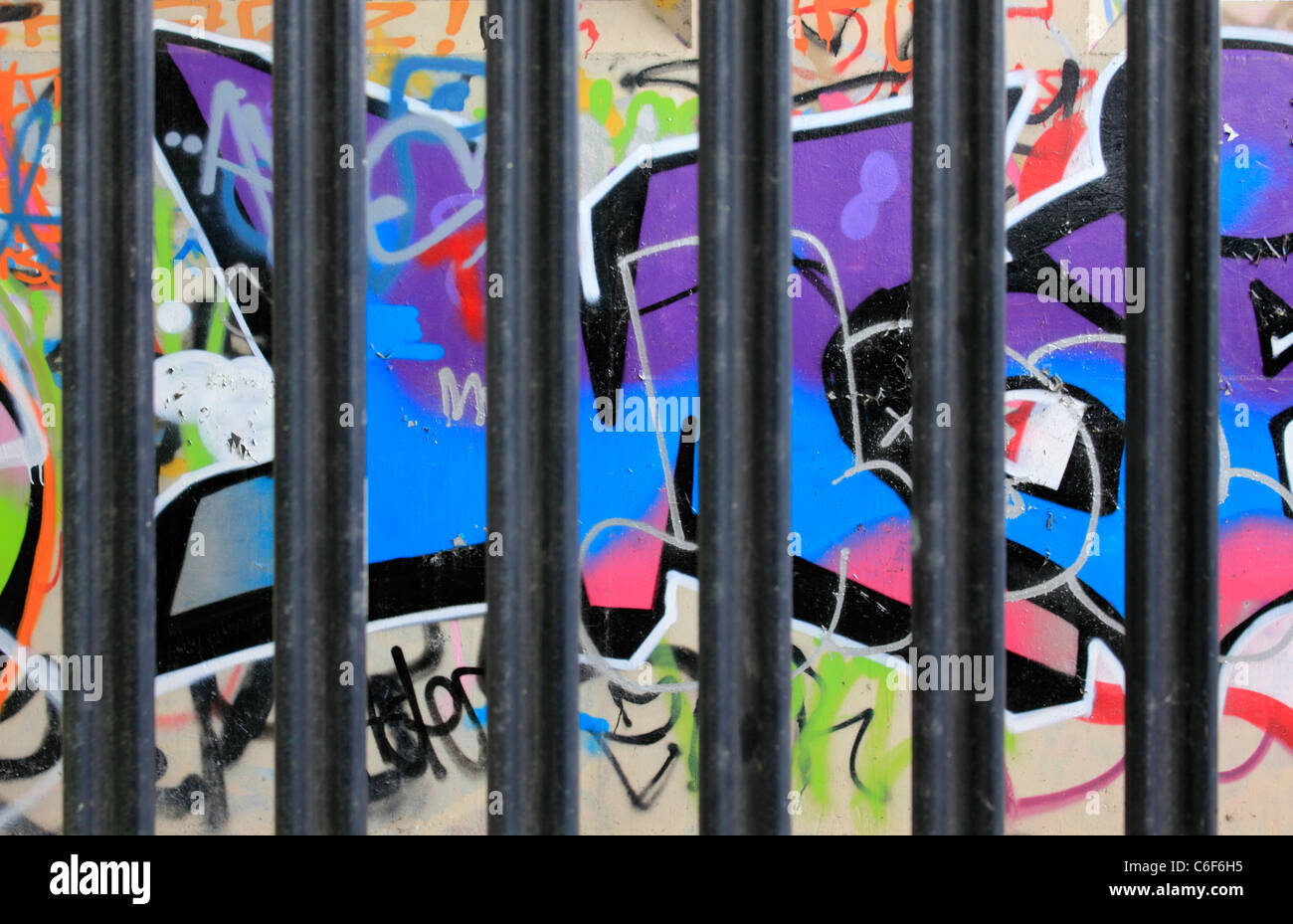 Graffiti behind bars on walls under the A316 flyover Hanworth, Surrey ...