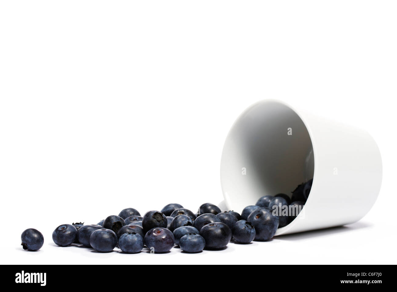 blueberries rolling from a fell over cup on white background Stock ...