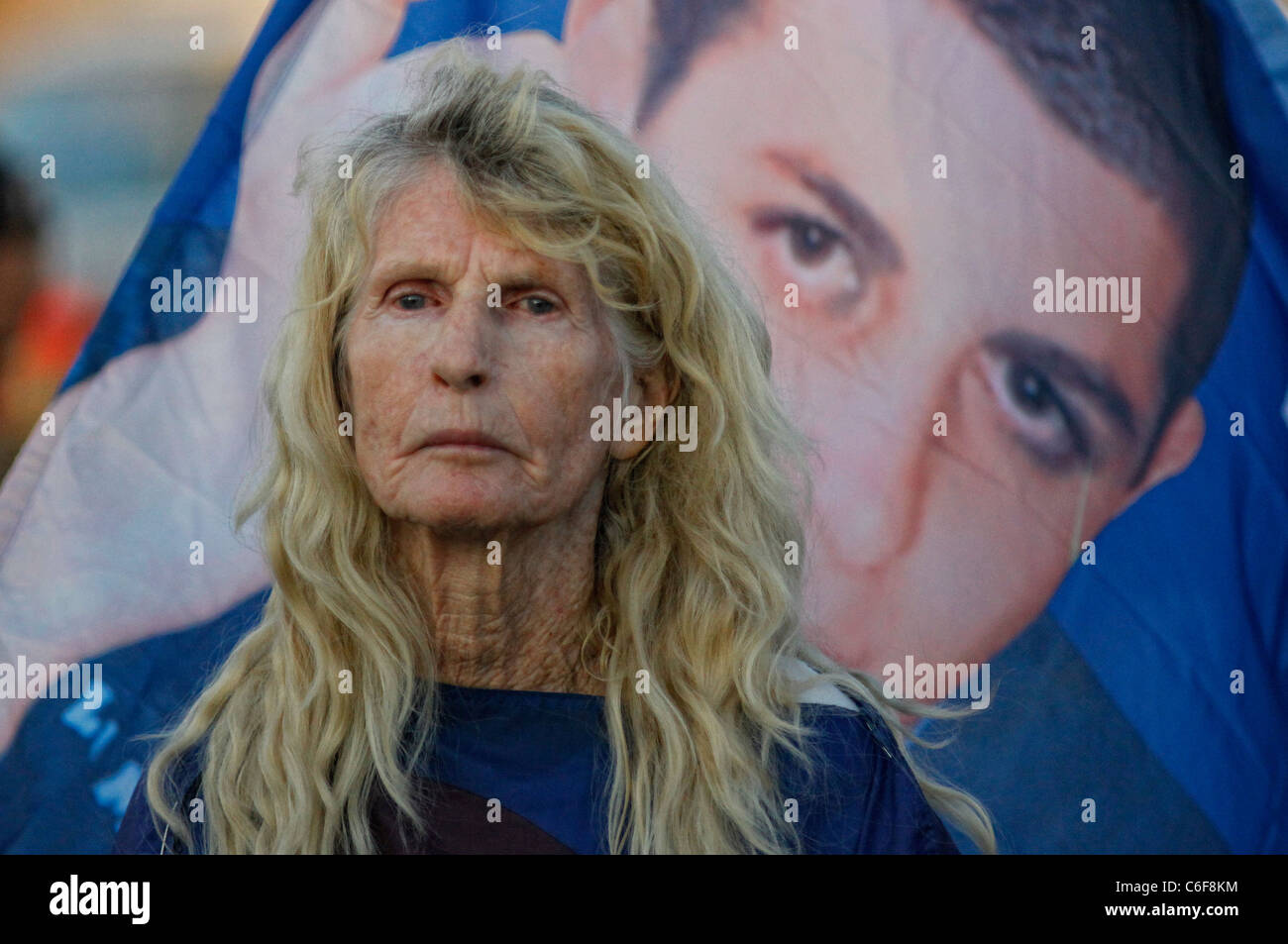 An Israeli woman stands in front of an image of captured Israeli ...