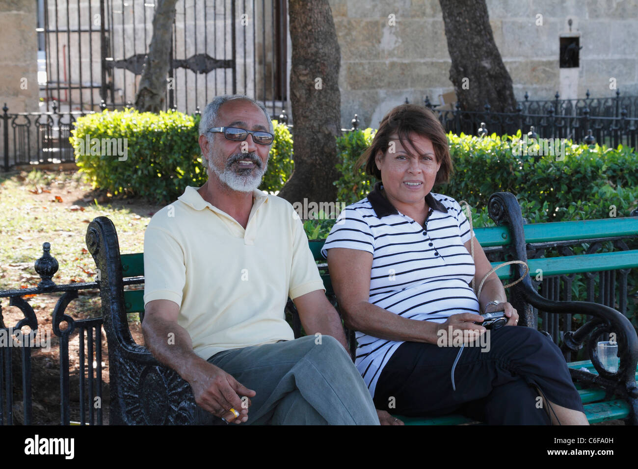 Elderly Cuban man and woman sitting on a bench in the park. Malecon ...