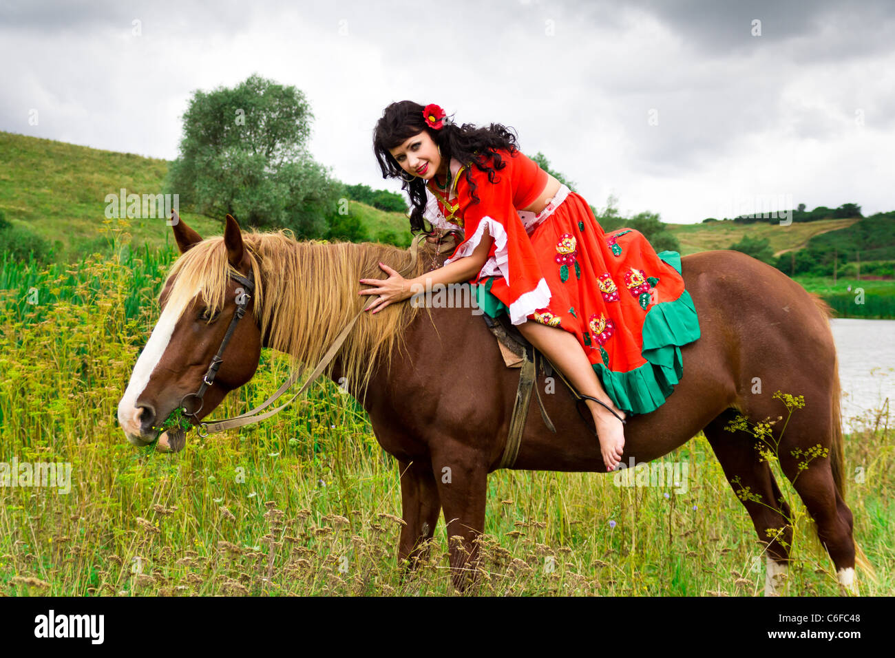 Beautiful gypsy girl riding a horse in the field Stock Photo - Alamy