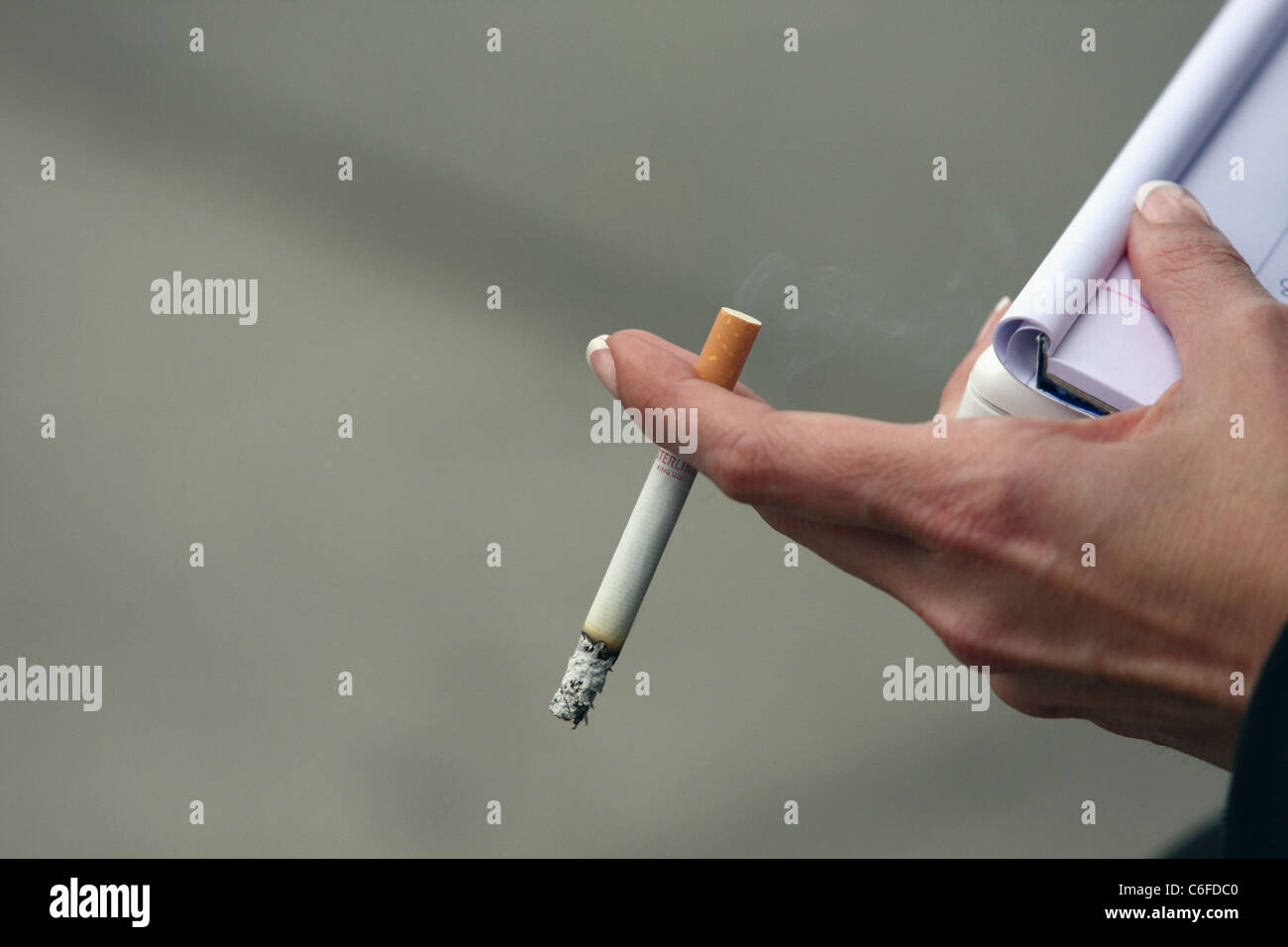 A hand holding a lighted cigarette and part of a notepad Stock Photo ...