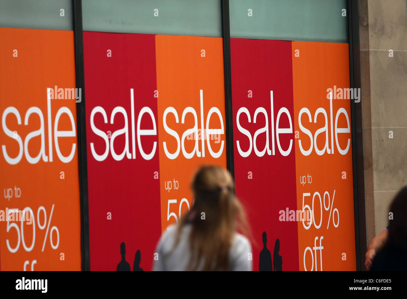 people walking by a sale sign in a shop window Stock Photo - Alamy
