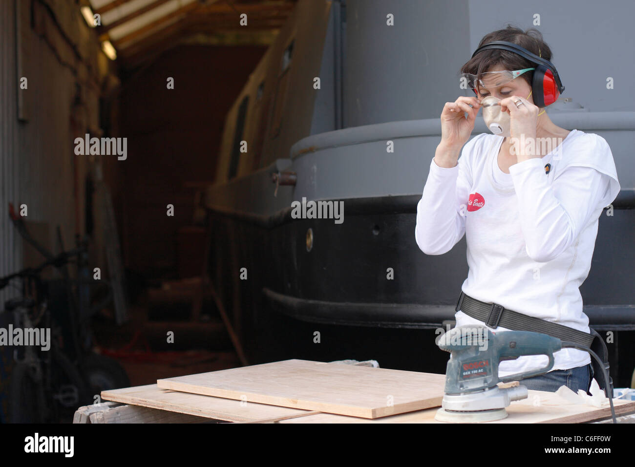 A young woman putting on a face mask, ear defenders and safety goggles ...