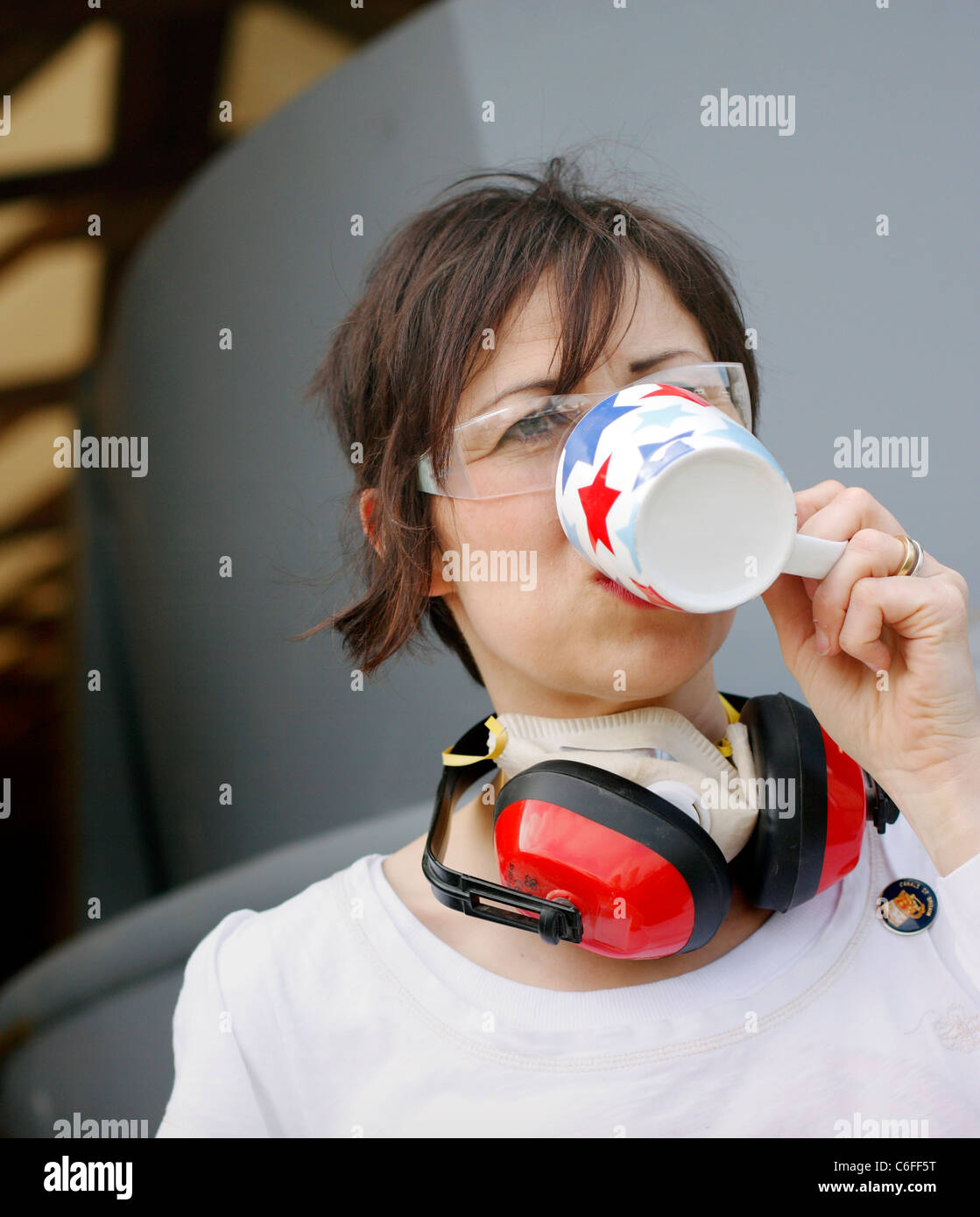 A woman drinking a cup of tea whilst having a break from work. Wearing ...
