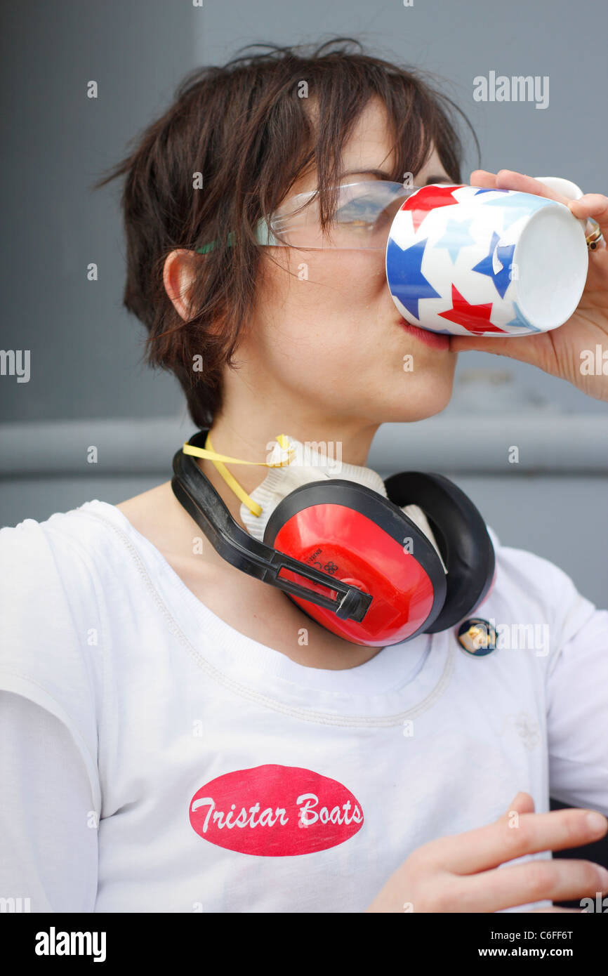 A woman drinking a cup of tea whilst having a break from work. Wearing ...