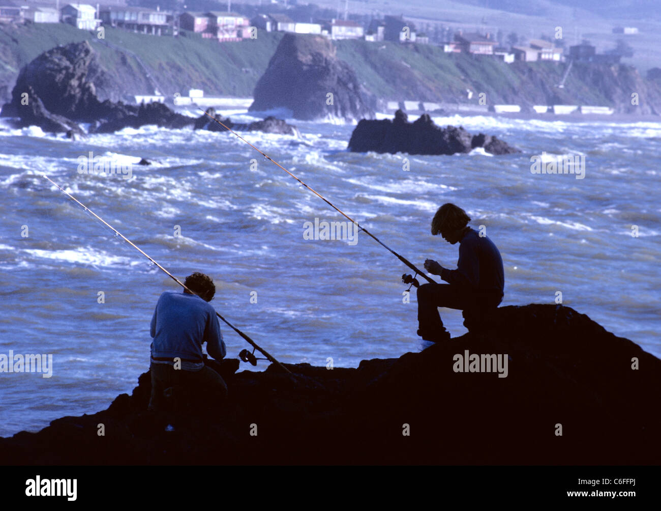 two teen boys fish off rocks along Mendocino County coast in Northern ...