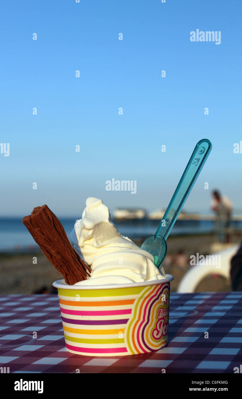 Soft ice cream in a tub with spoon and flake, on a red and white ...