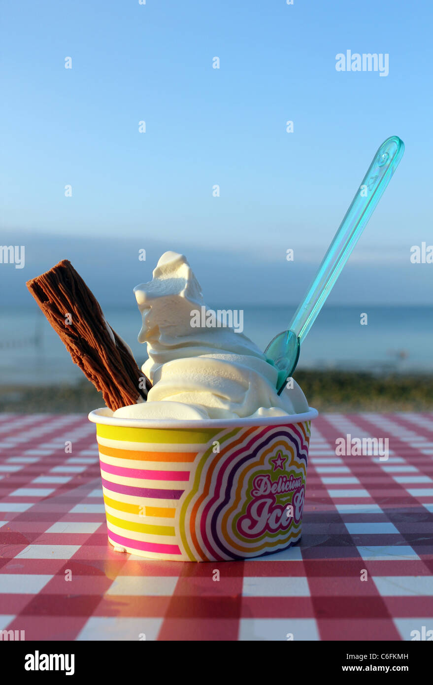 Soft ice cream in a tub with spoon and flake, on a red and white ...