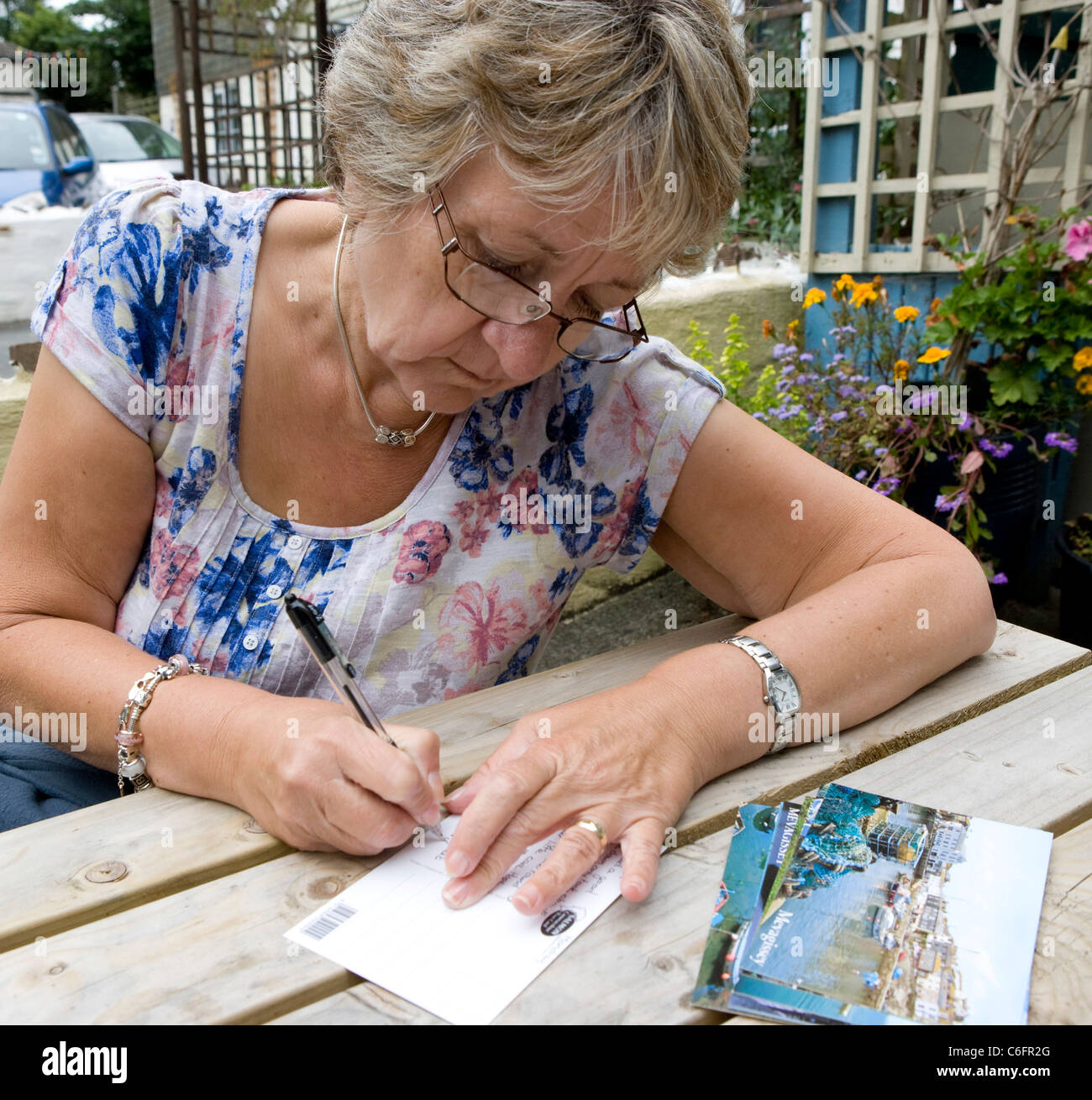 A mature lady writing postcards from holiday Stock Photo - Alamy