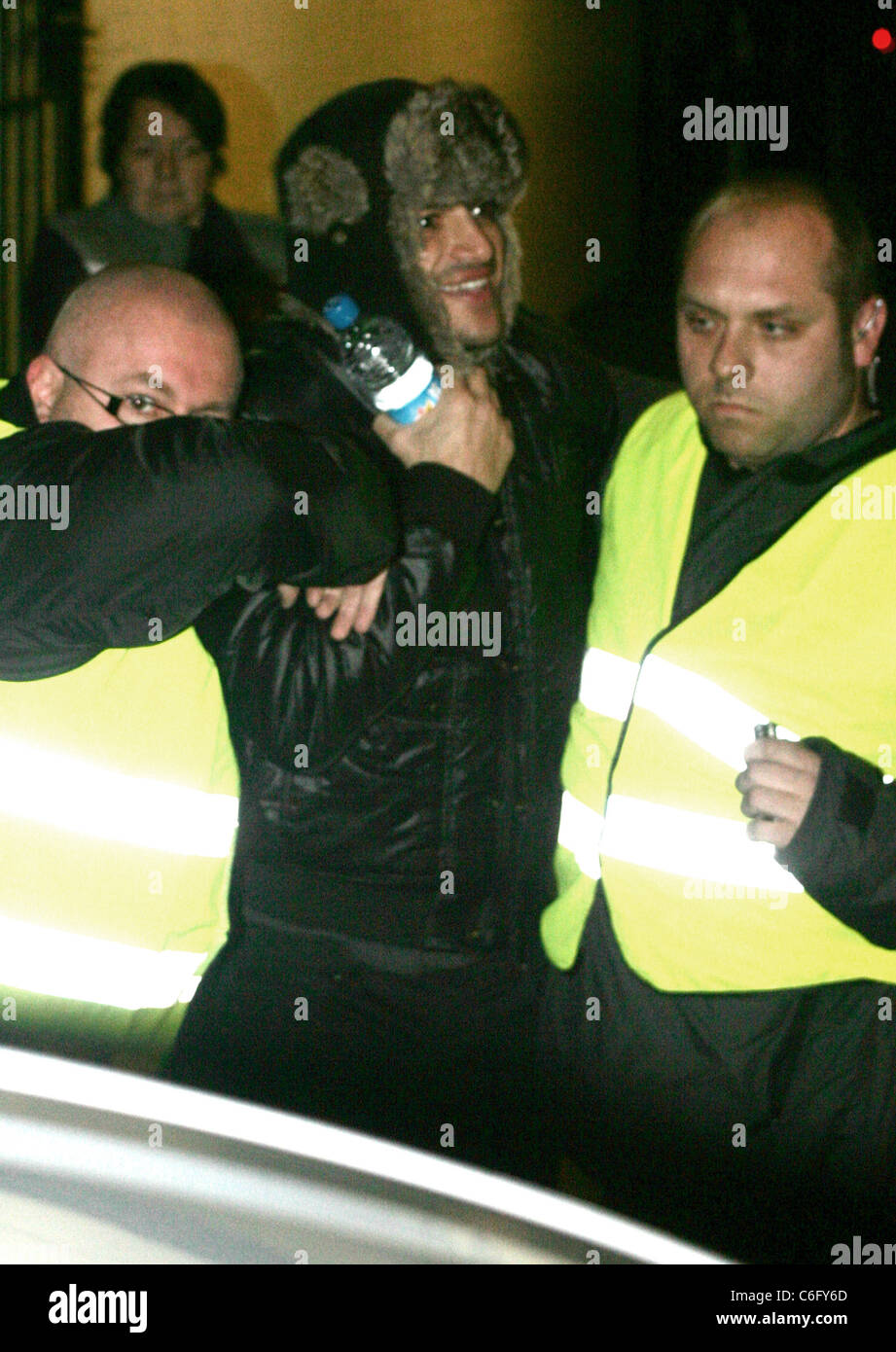 Peter Andre wearing a fur hat is protected by security as he leaves the ...