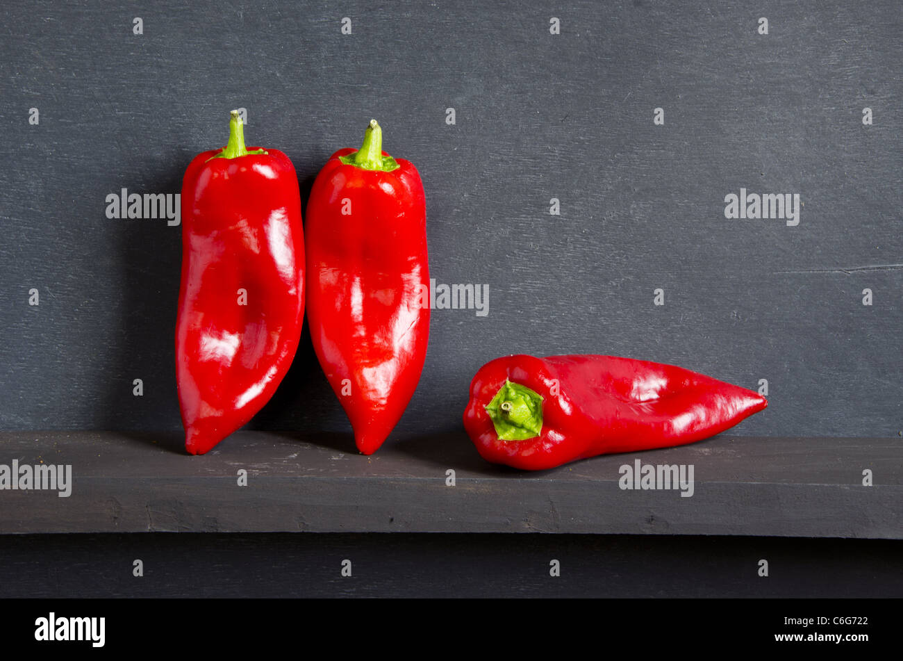 three red peppers on black background Stock Photo - Alamy