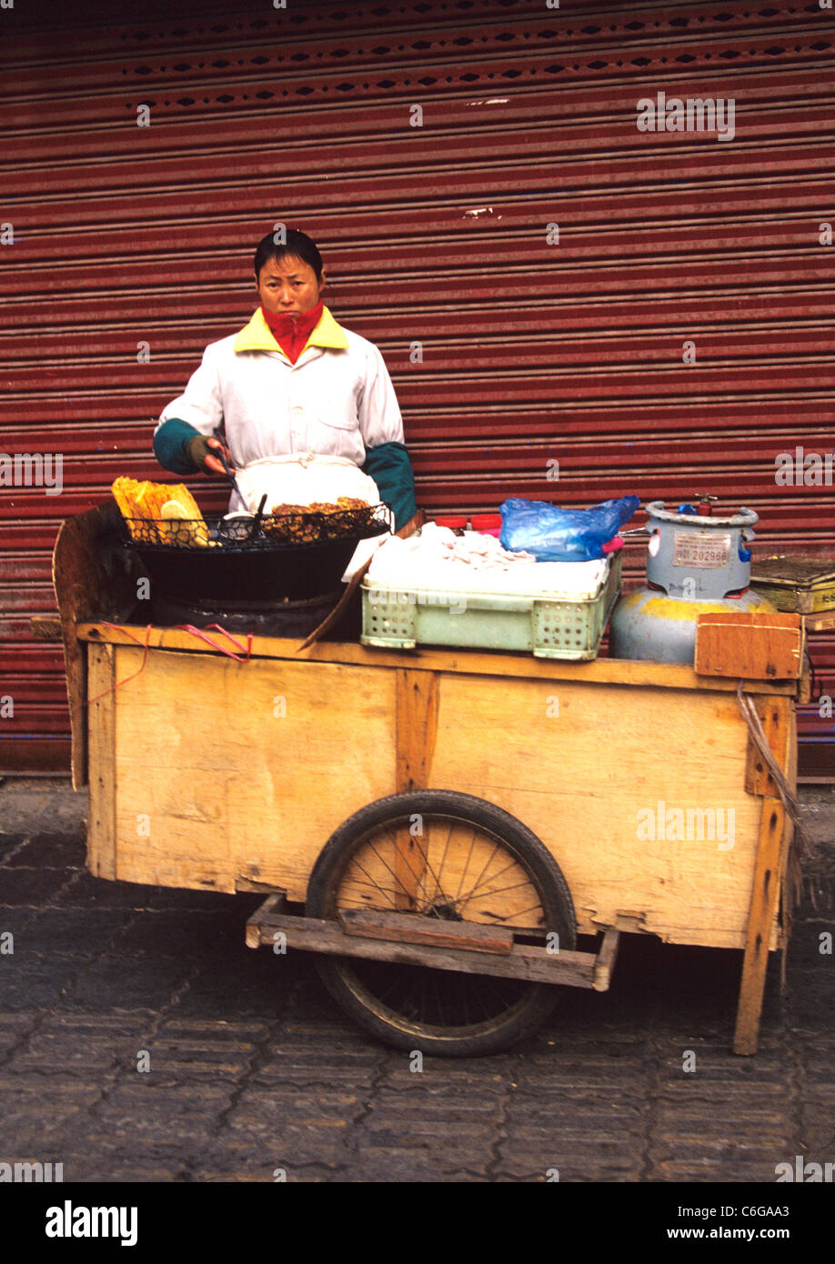 woman cooks and sells pastry from homemade food cart on a street in ...