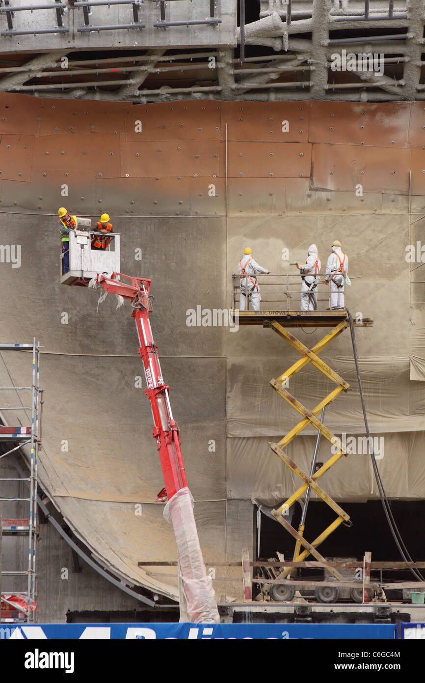 Construction workers using vertical lift platforms wearing safety ...