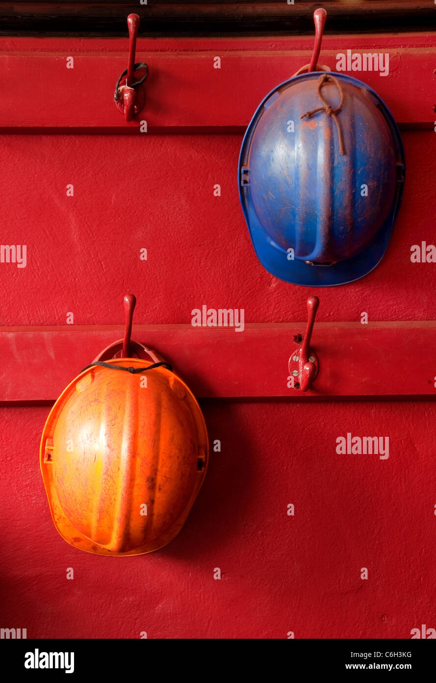 Red and blue hard hats hanging on wall Stock Photo - Alamy