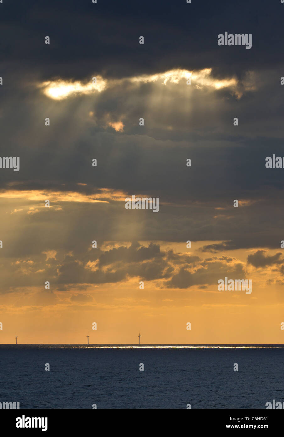 Rays of the late afternoon sun shining through clouds onto an offshore ...