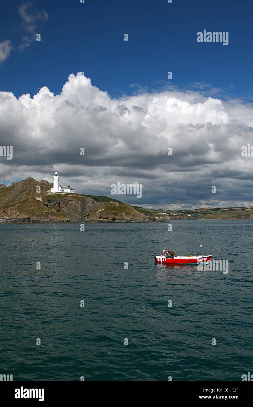 A small fishing boat anchored off Start Point lighthouse on the coast ...