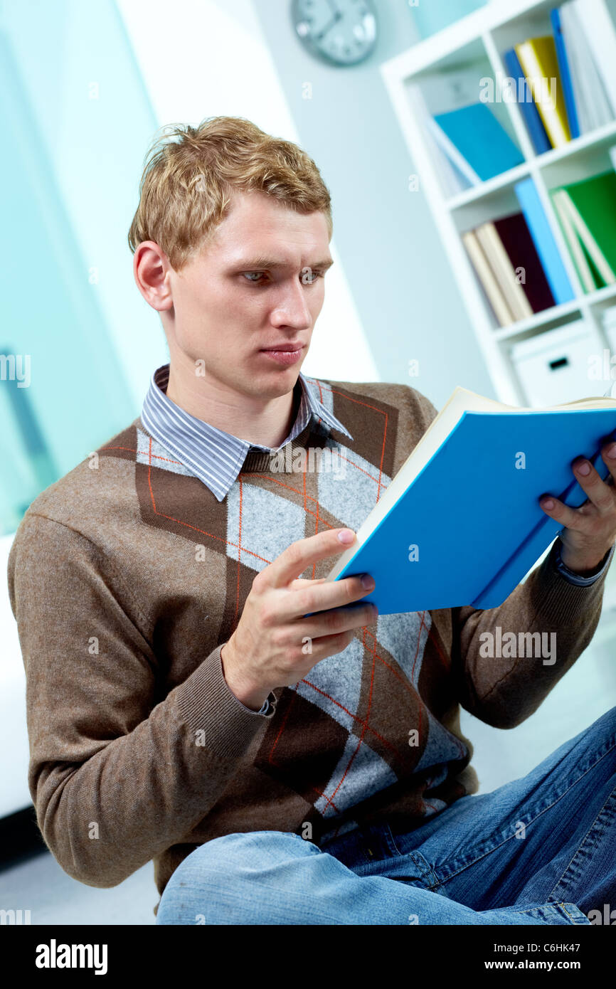 Image of serious student sitting on the floor and reading book Stock ...
