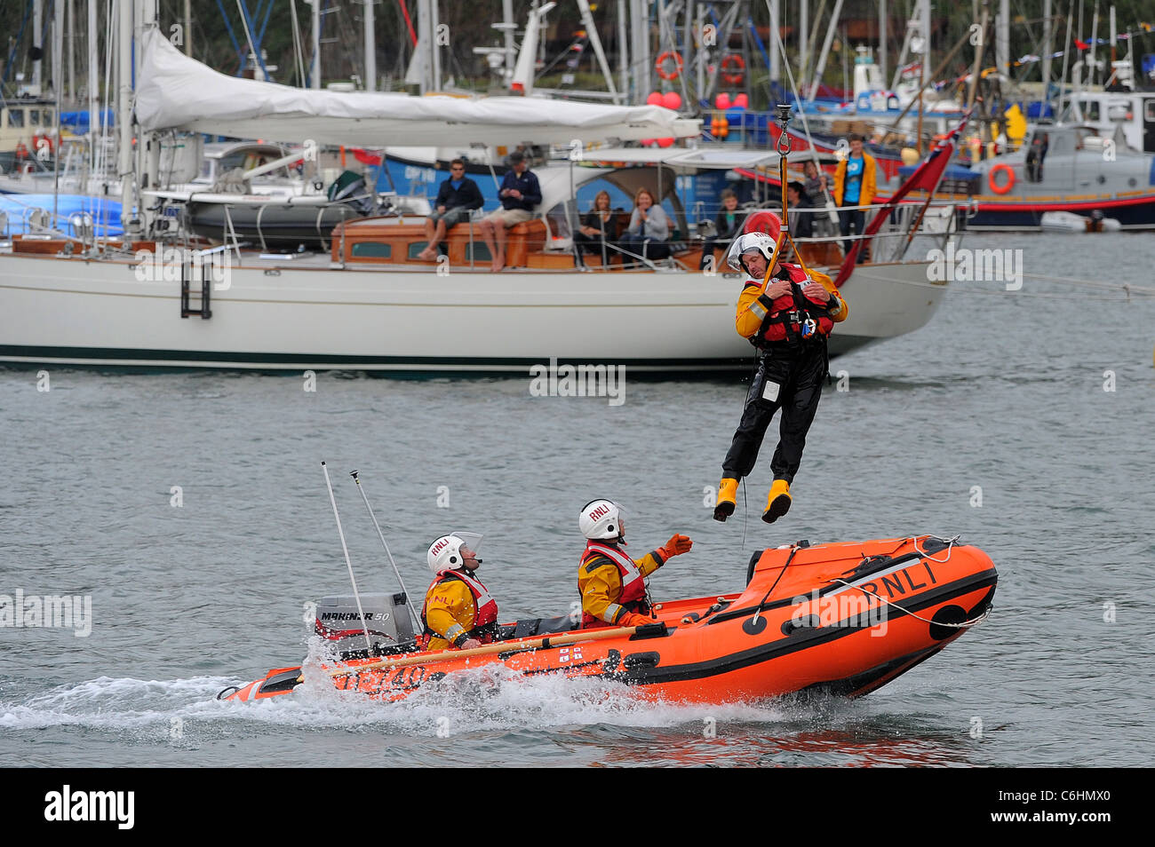 An RNLI Lifeboatman is winched back into an inshore lifeboat from a ...
